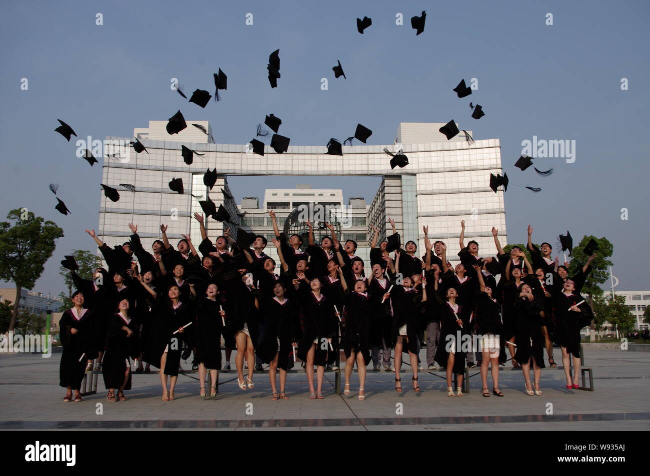 --FILE--Chinese graduates throw their academic hats into the air after ...