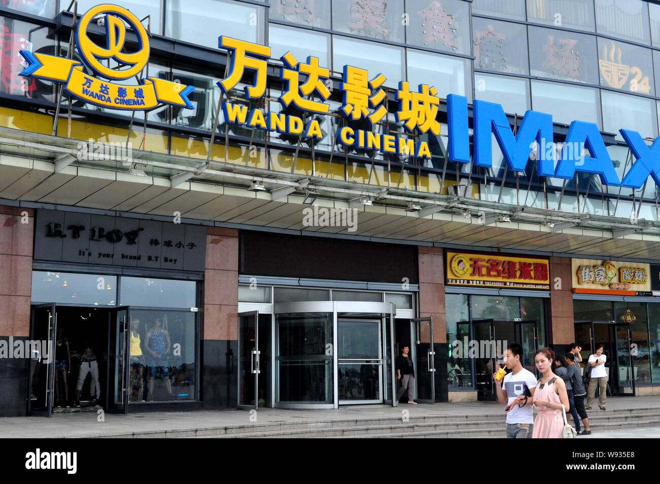 --FILE--Pedestrians walk past a branch of Wanda Cinema with the logo of ...