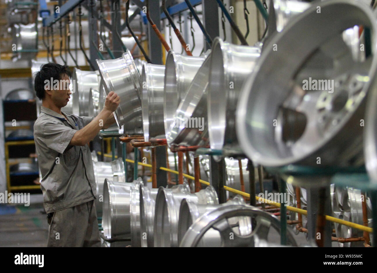 --FILE--A Chinese worker examines car rims on the production line at a ...