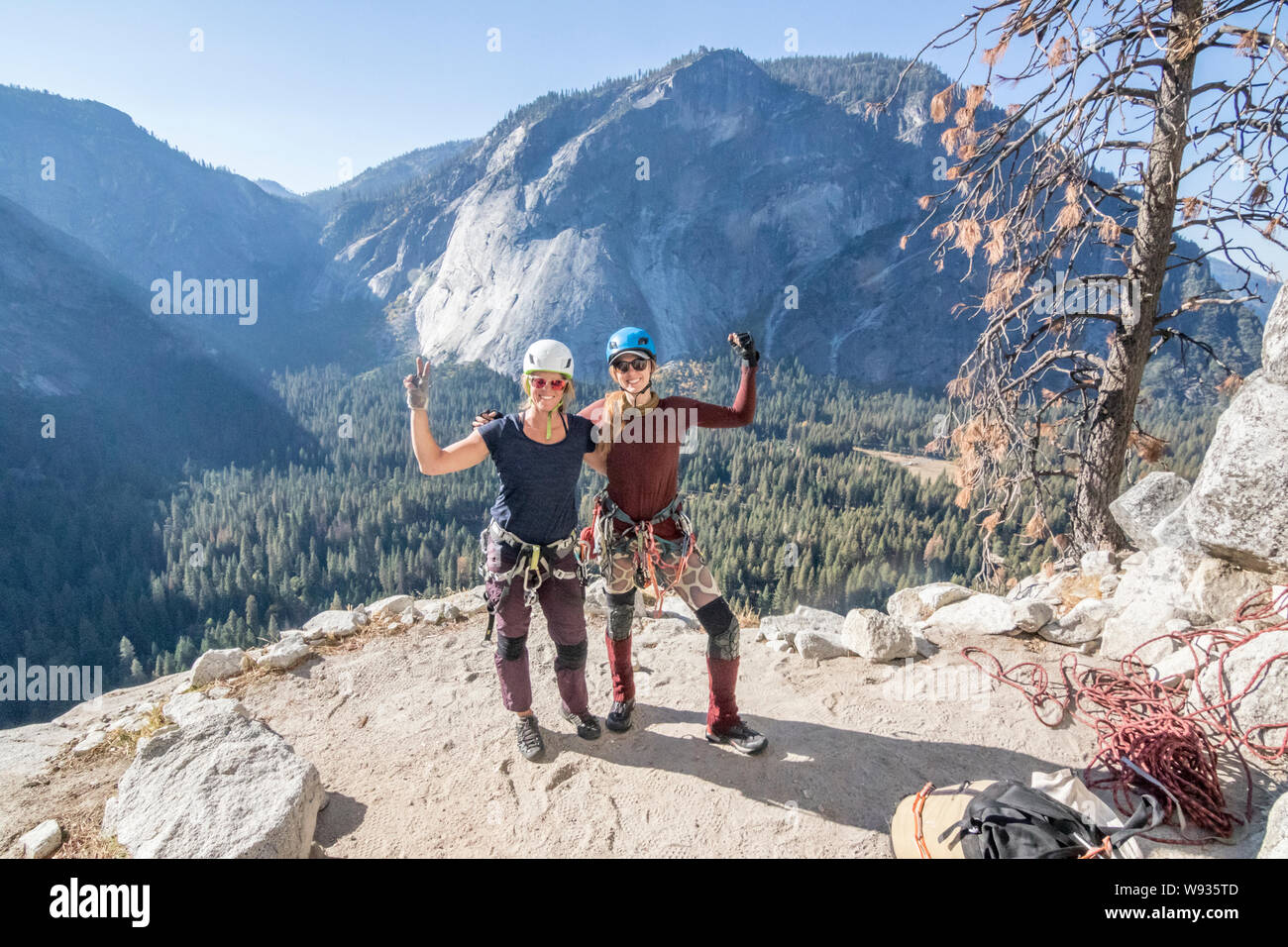 Two women pose victoriously after completing their climbing objective ...