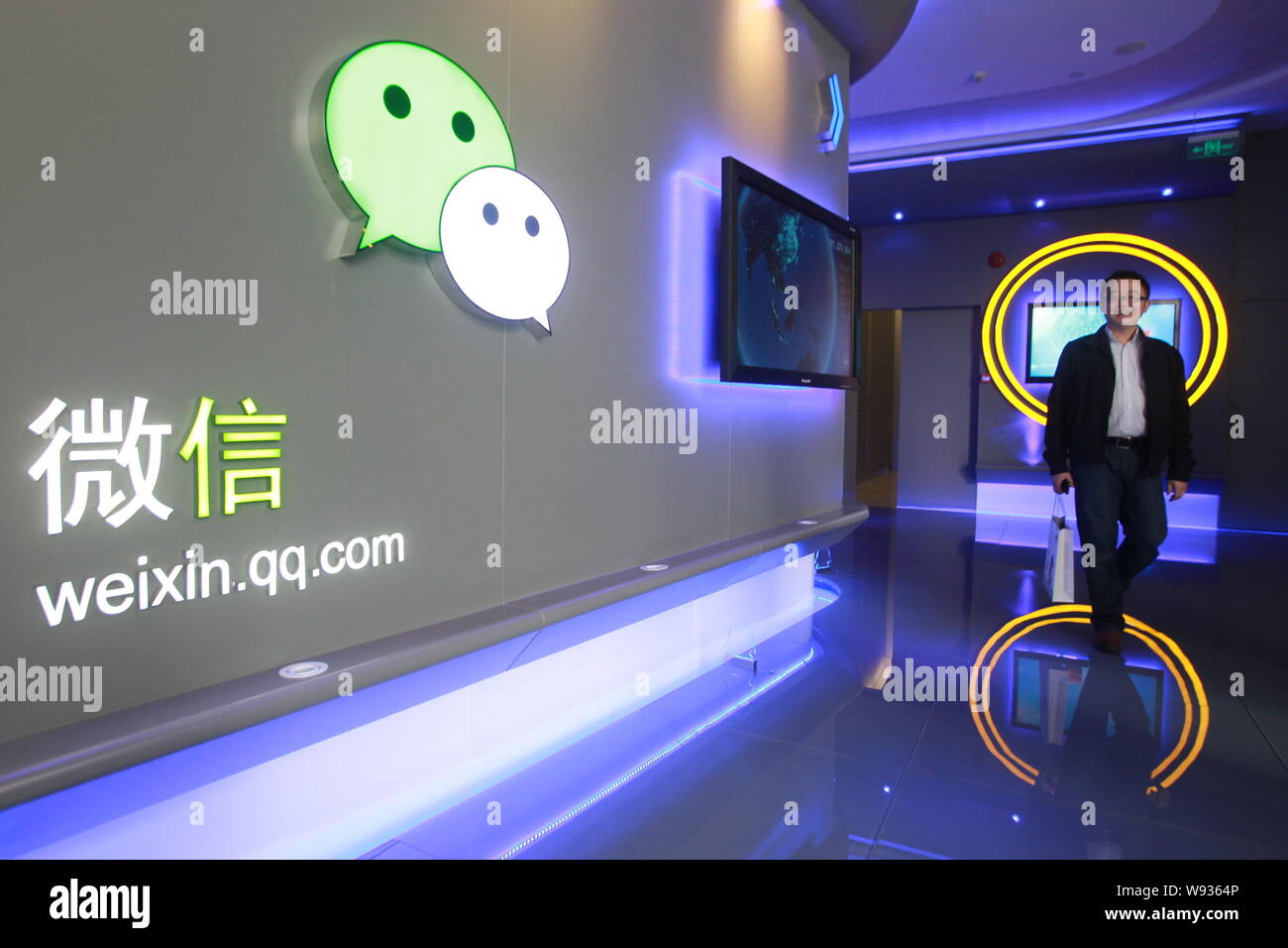 --FILE--A Chinese employee walks past a logo of Weixin.com (Wechat) at ...