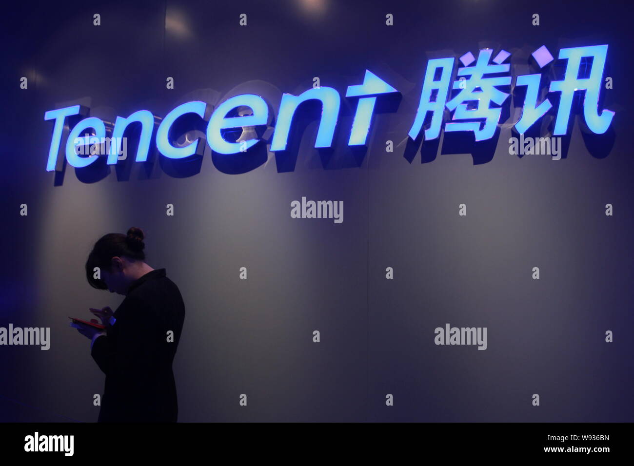 --FILE--A Chinese employee uses her mobile phone in front of a signage ...