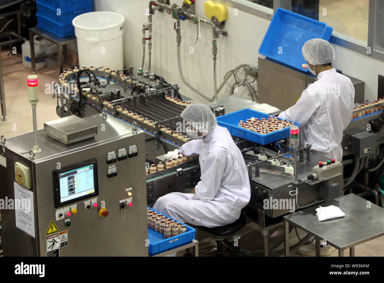 --FILE--Factory workers watch bottles of Yakult fermented milk drink ...