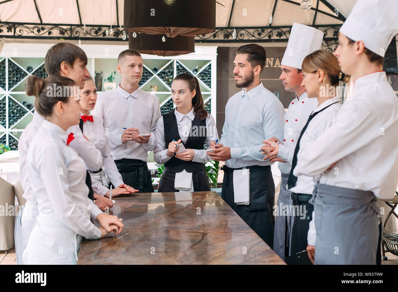 Restaurant manager and his staff in terrace. interacting to head chef ...