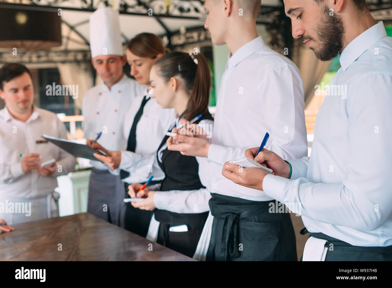 Restaurant manager and his staff in terrace. interacting to head chef ...