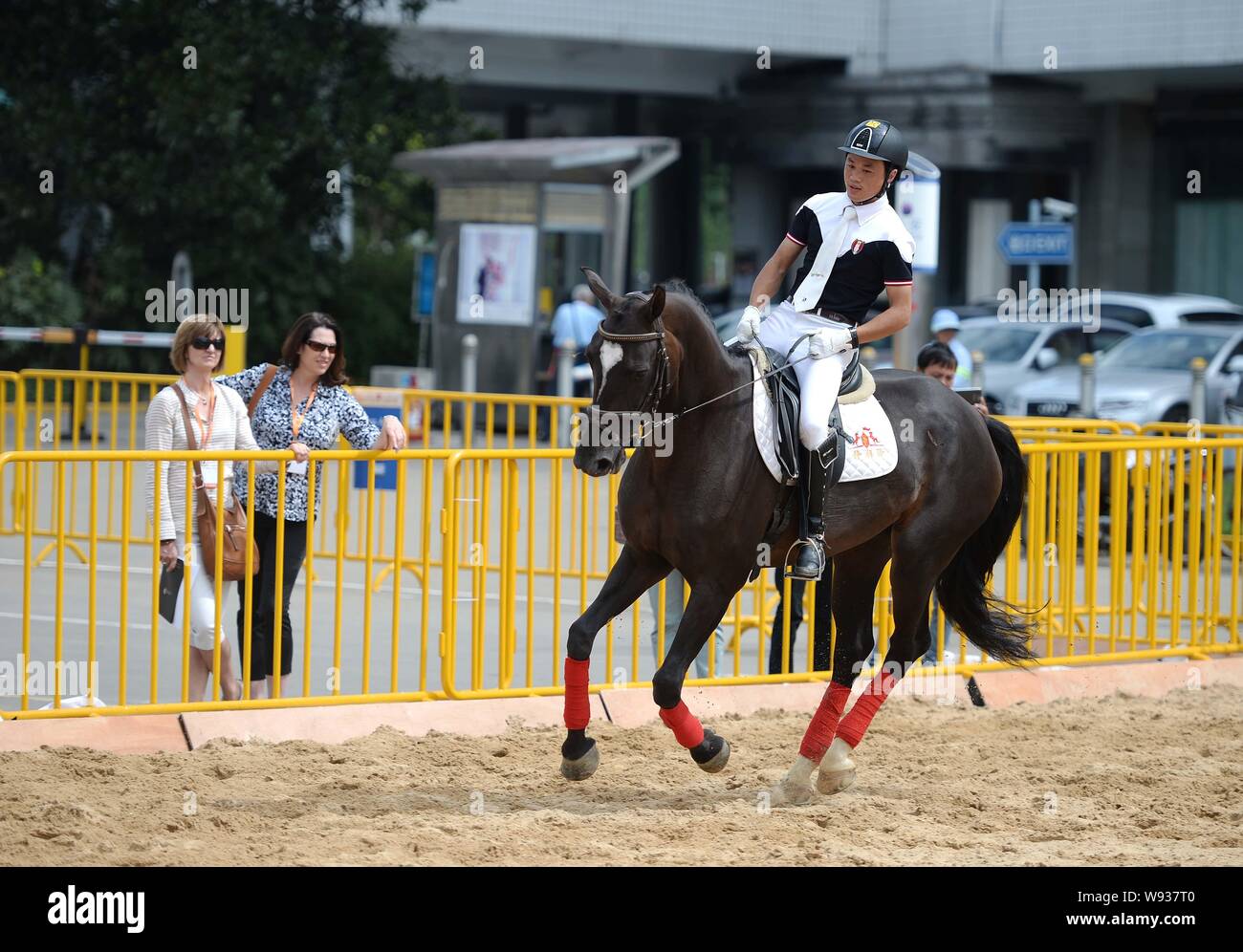 Foreign visitors watch a Chinese horse trainer riding a horse during ...
