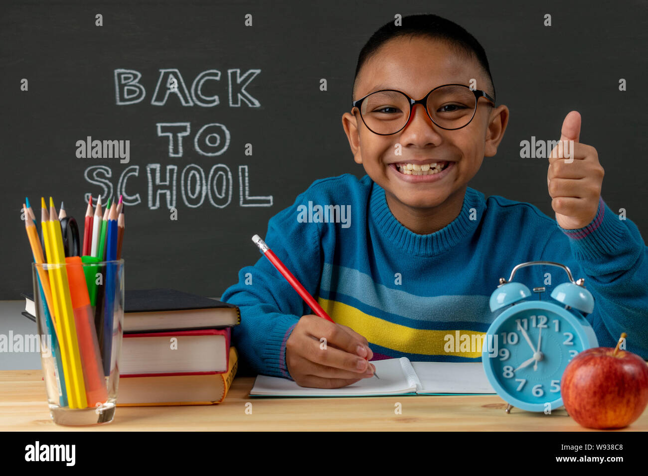 Pupil from primary school writing a book with raising hand. Child is ...