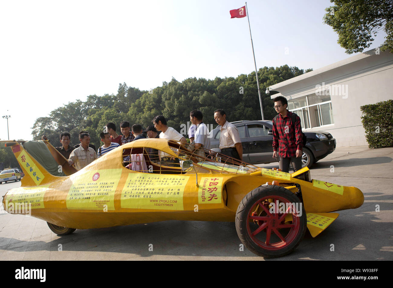 Passers-by look at a homemade jet-shaped three-wheeled racing car in ...