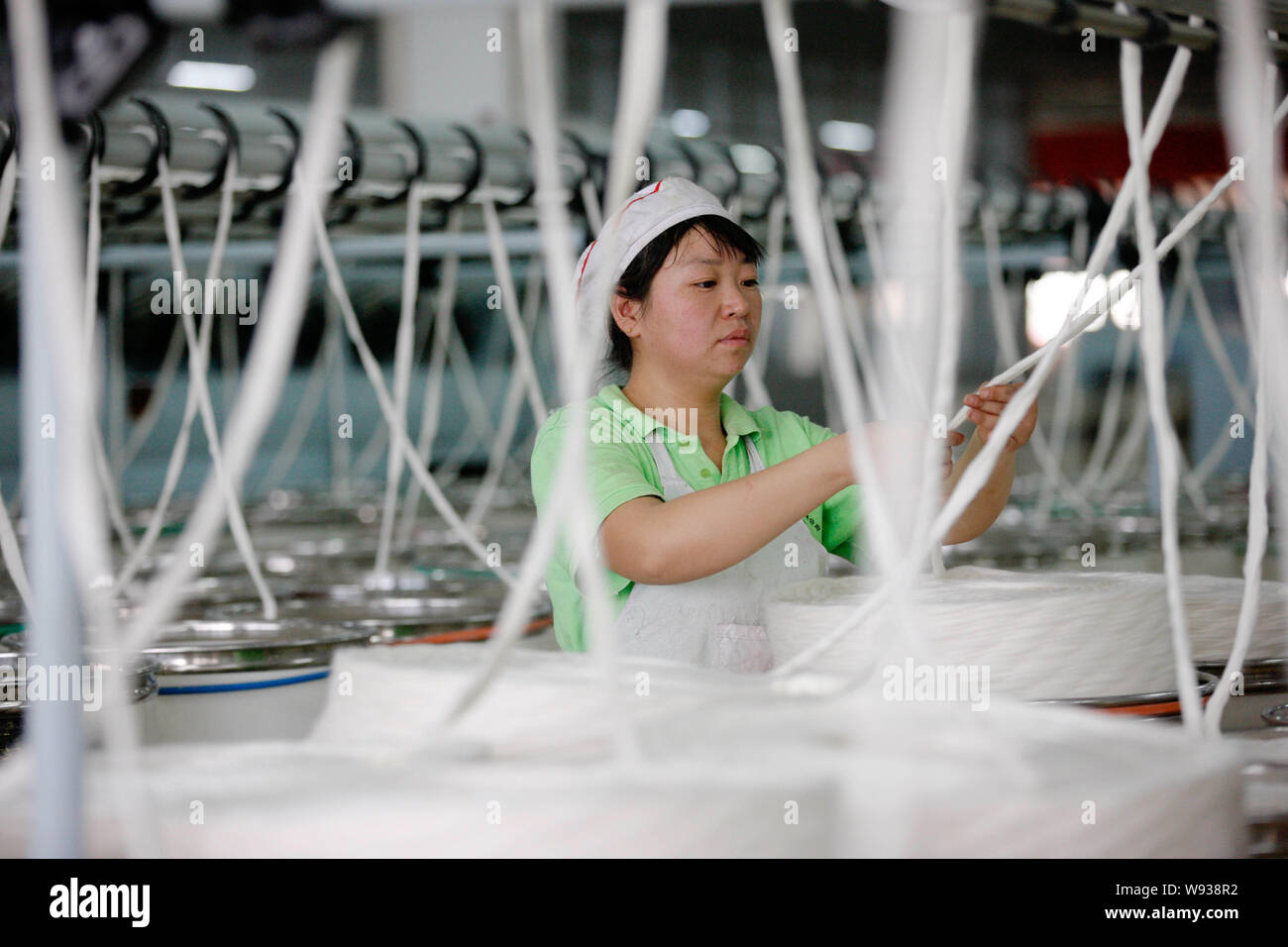A female Chinese worker handles production of yarn to be exported to South Korea at a textile ...