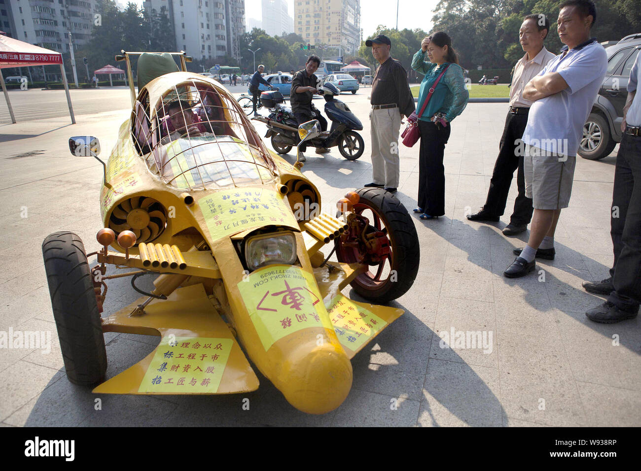 Passers-by look at a homemade jet-shaped three-wheeled racing car in ...
