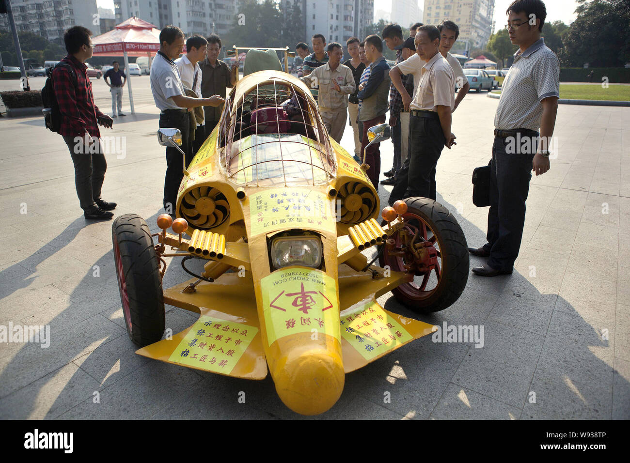 Passers-by look at a homemade jet-shaped three-wheeled racing car in ...