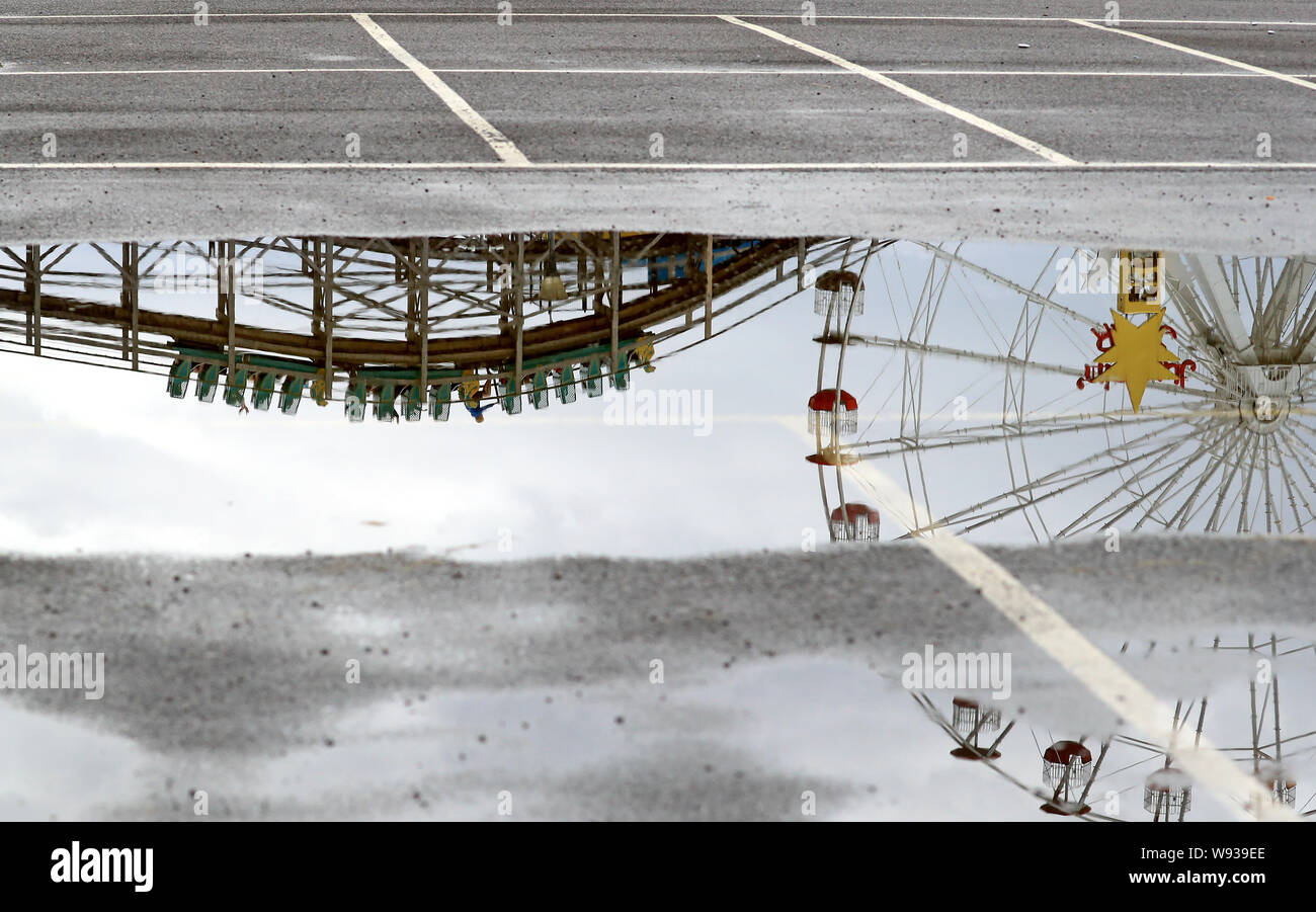The Scenic Railway and Big Wheel are reflected in puddles in empty ...
