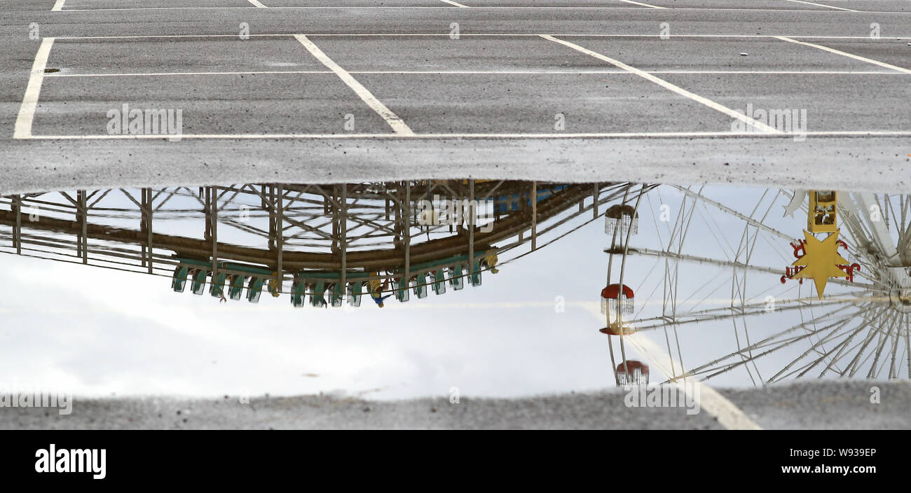 The Scenic Railway and Big Wheel are reflected in puddles in empty ...