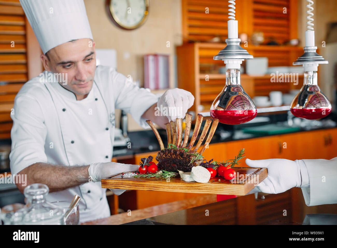 The cook passes the waiter the finished dish. rack of lamb Stock Photo ...