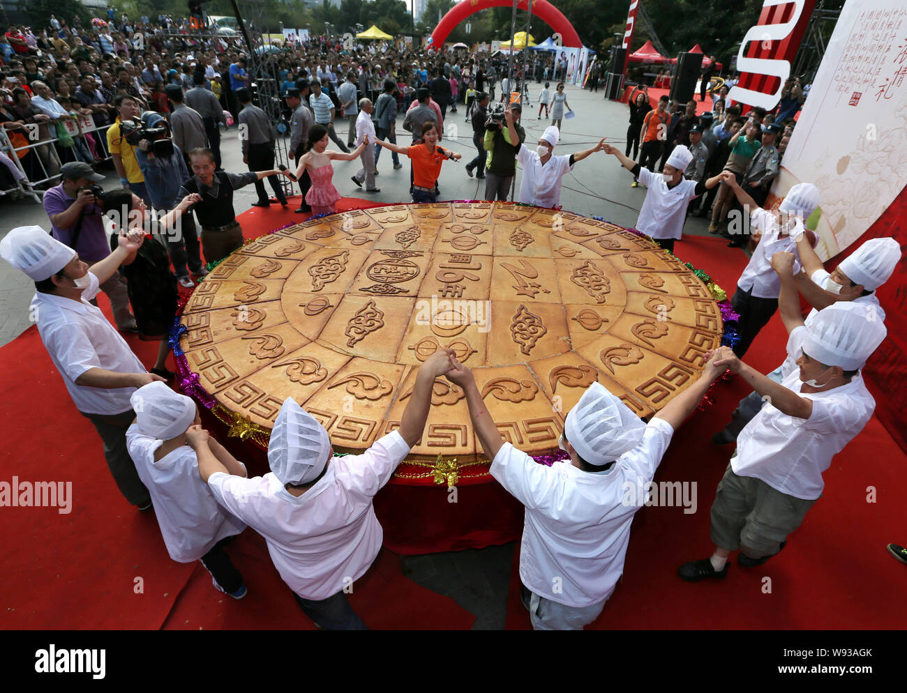 --FILE--Chinese cooks and guests stand hand in hand around a giant ...