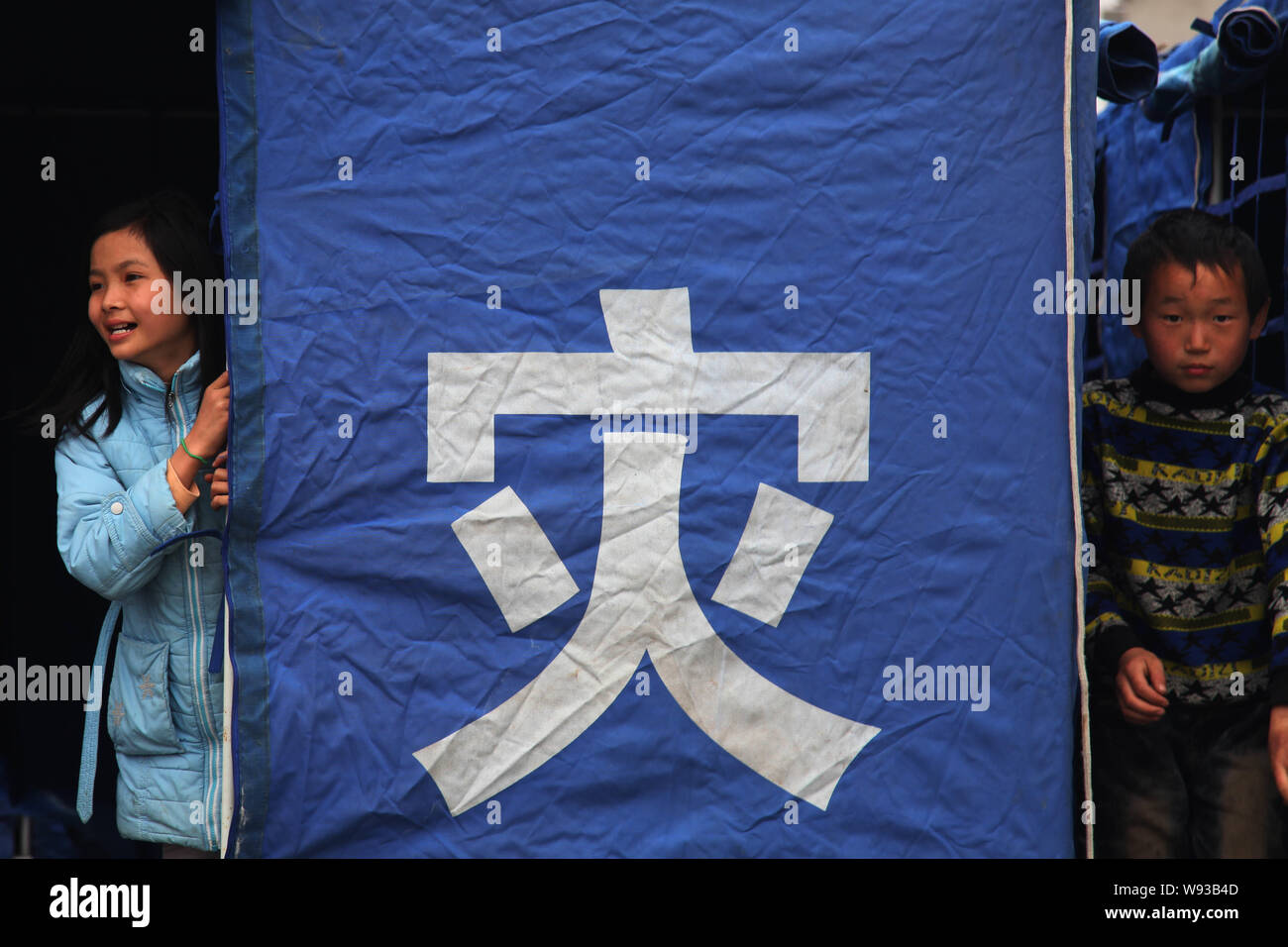 Young kids look out from a rescue tent with a Chinese character for ...