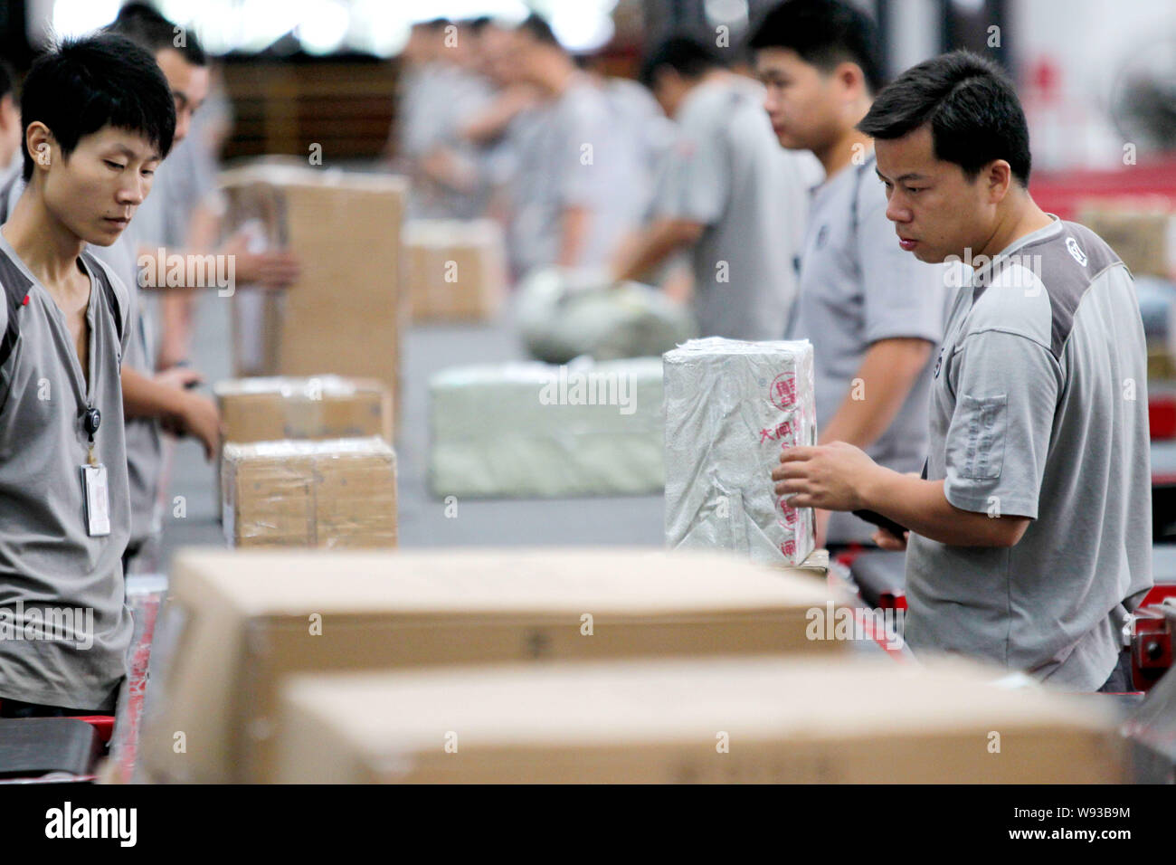 Chinese workers sort parcels, most of which come from online shopping, at a transhipment center ...