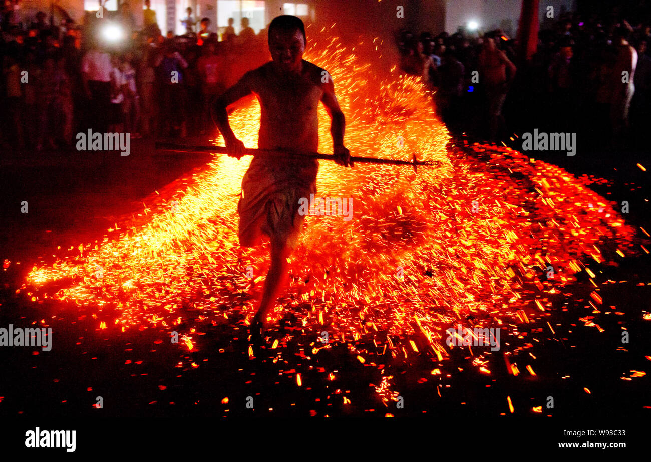 A local Chinese man runs barefoot across burning ambers during a ...