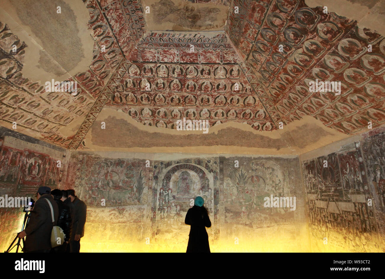 Visitors view replicas in a replicated chamber of the Mogao Grottoes during the Dunhuang Art ...