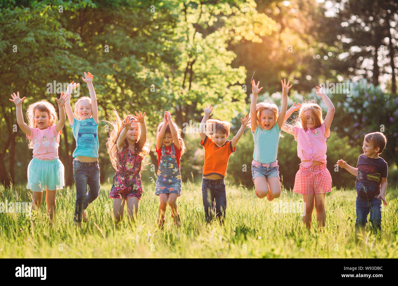 Group of friends running happily together in the grass and jumping ...