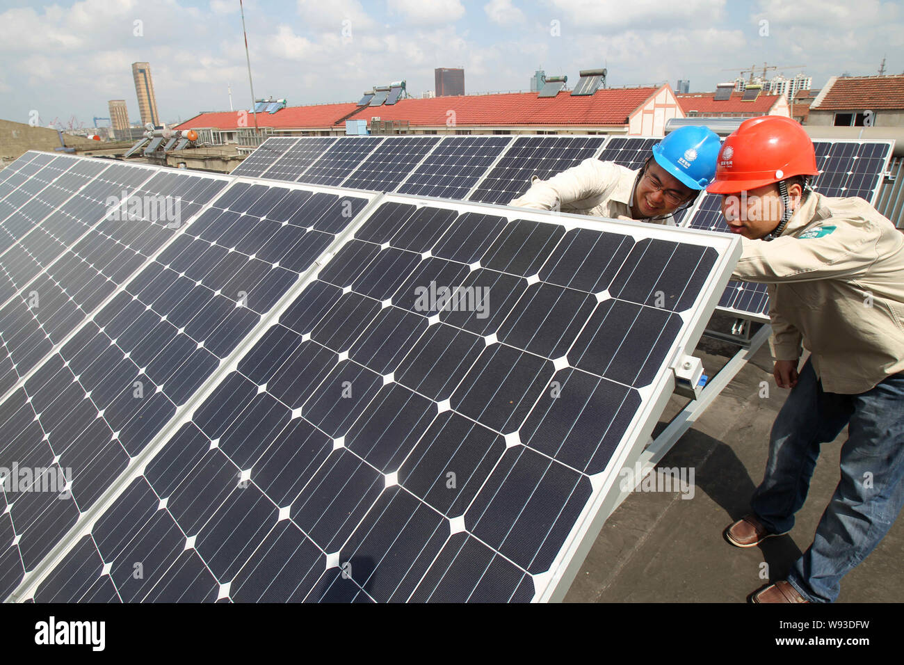 Technicians check solar panels at a rooftop photovoltaic (PV) power ...