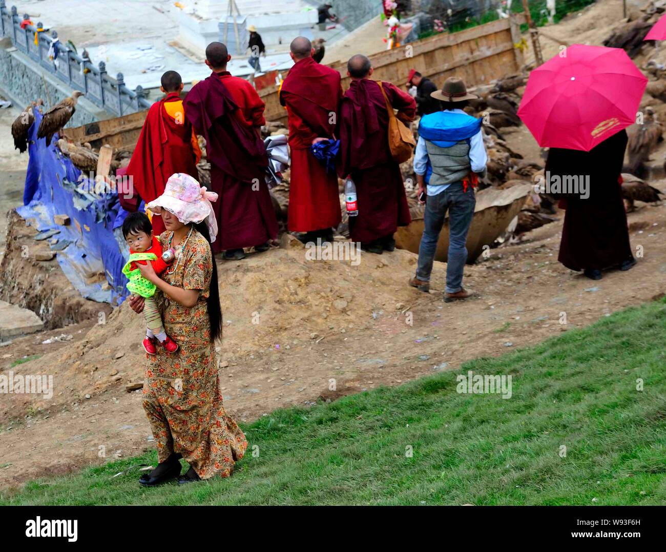 Local lamas and tourists look at a flock of vultures after a sky burial ...