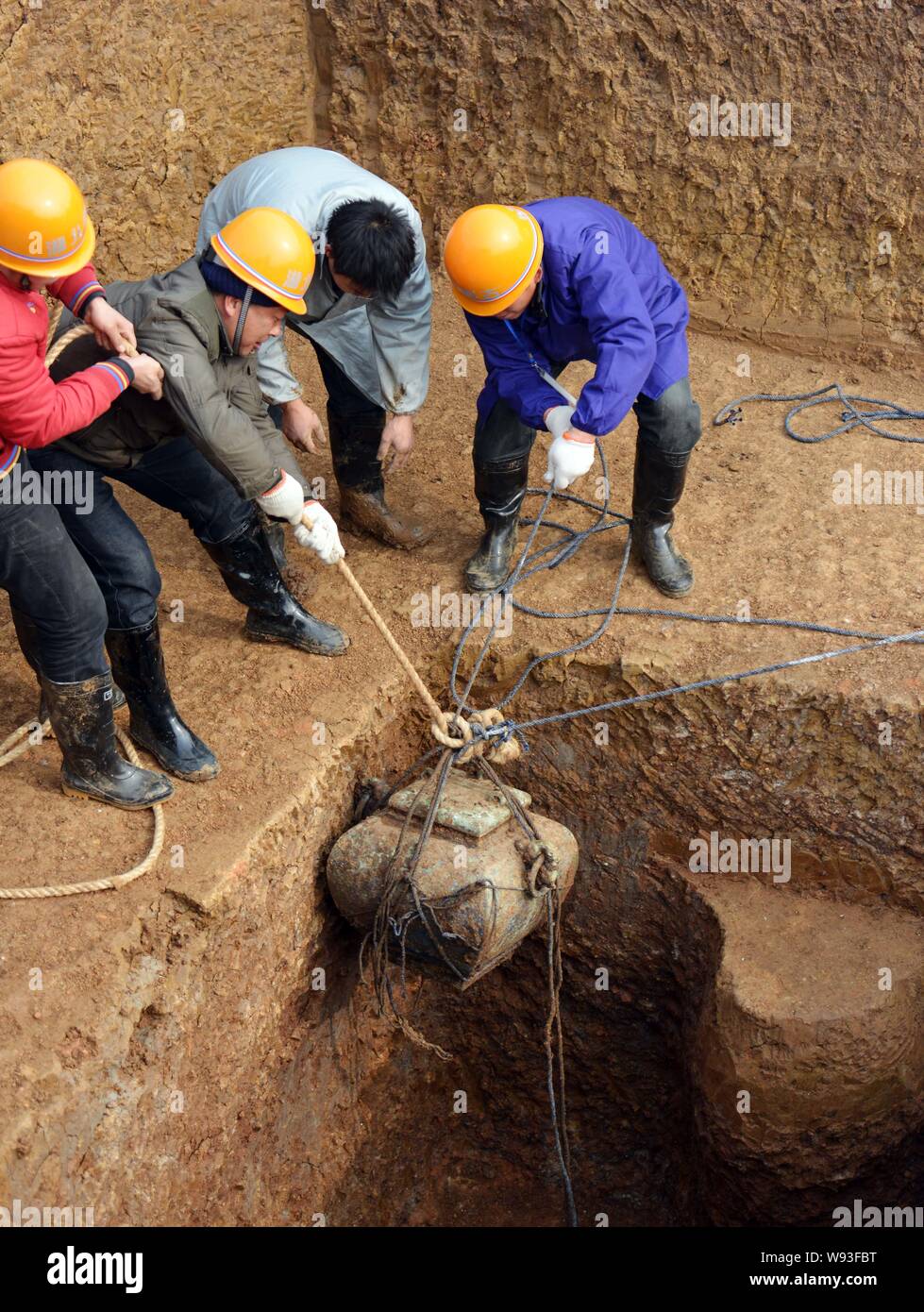 Chinese archaeologists carefully lift a relic unearthed at an ...