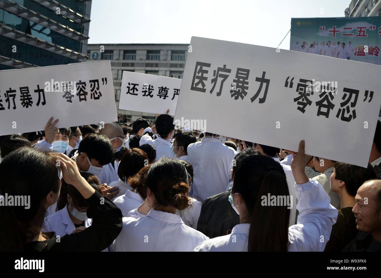 Chinese medical workers gather and hold up placards to protest against ...