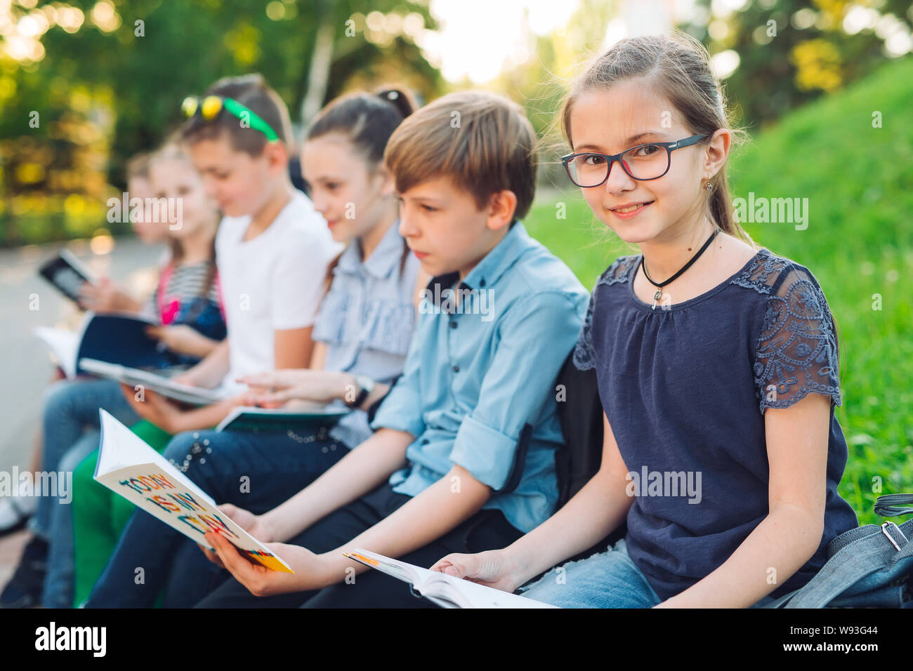 Happy Schoolmates Portrait. Schoolmates seating with books in a wooden ...