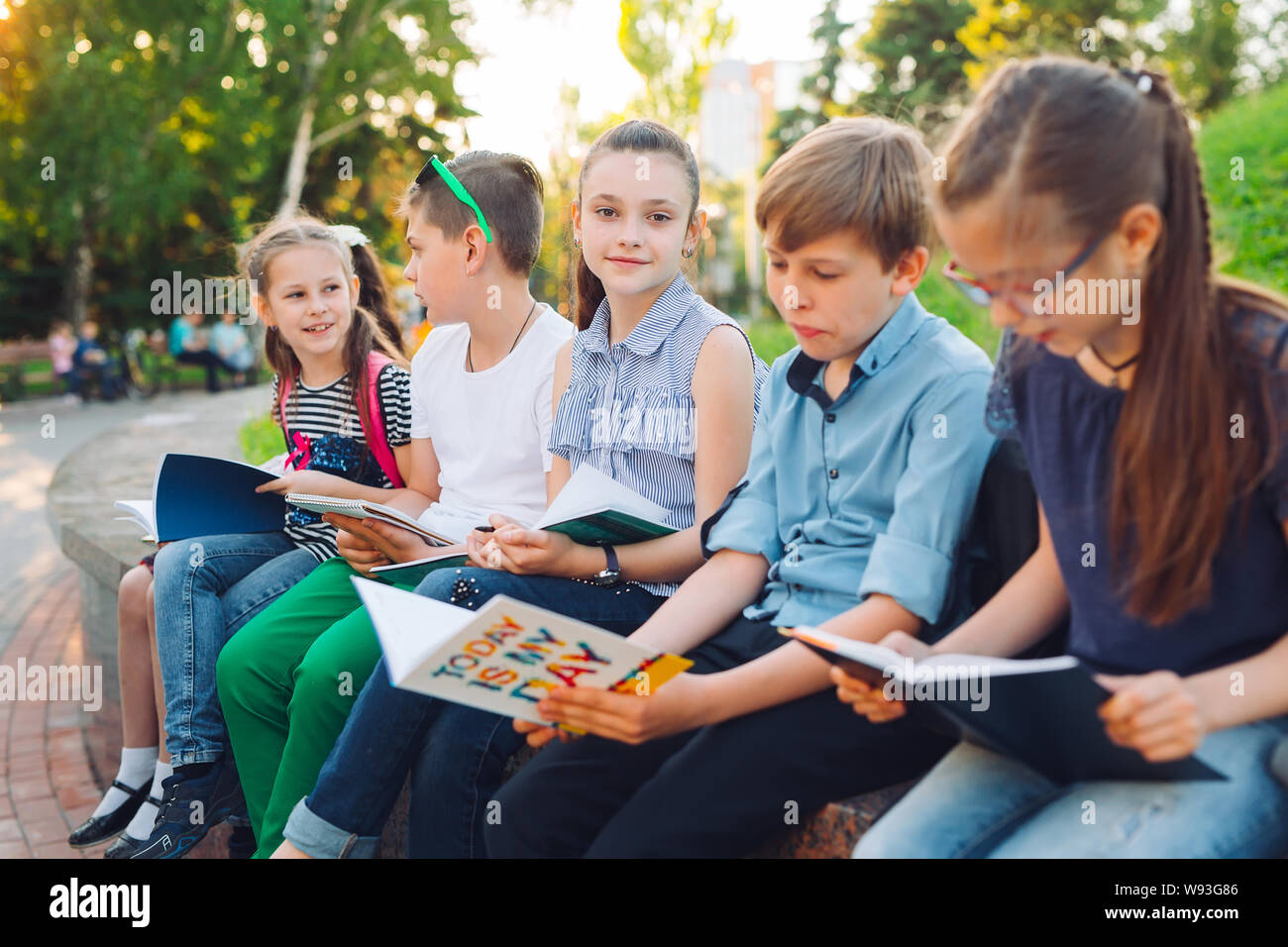 Happy Schoolmates Portrait. Schoolmates seating with books in a wooden ...