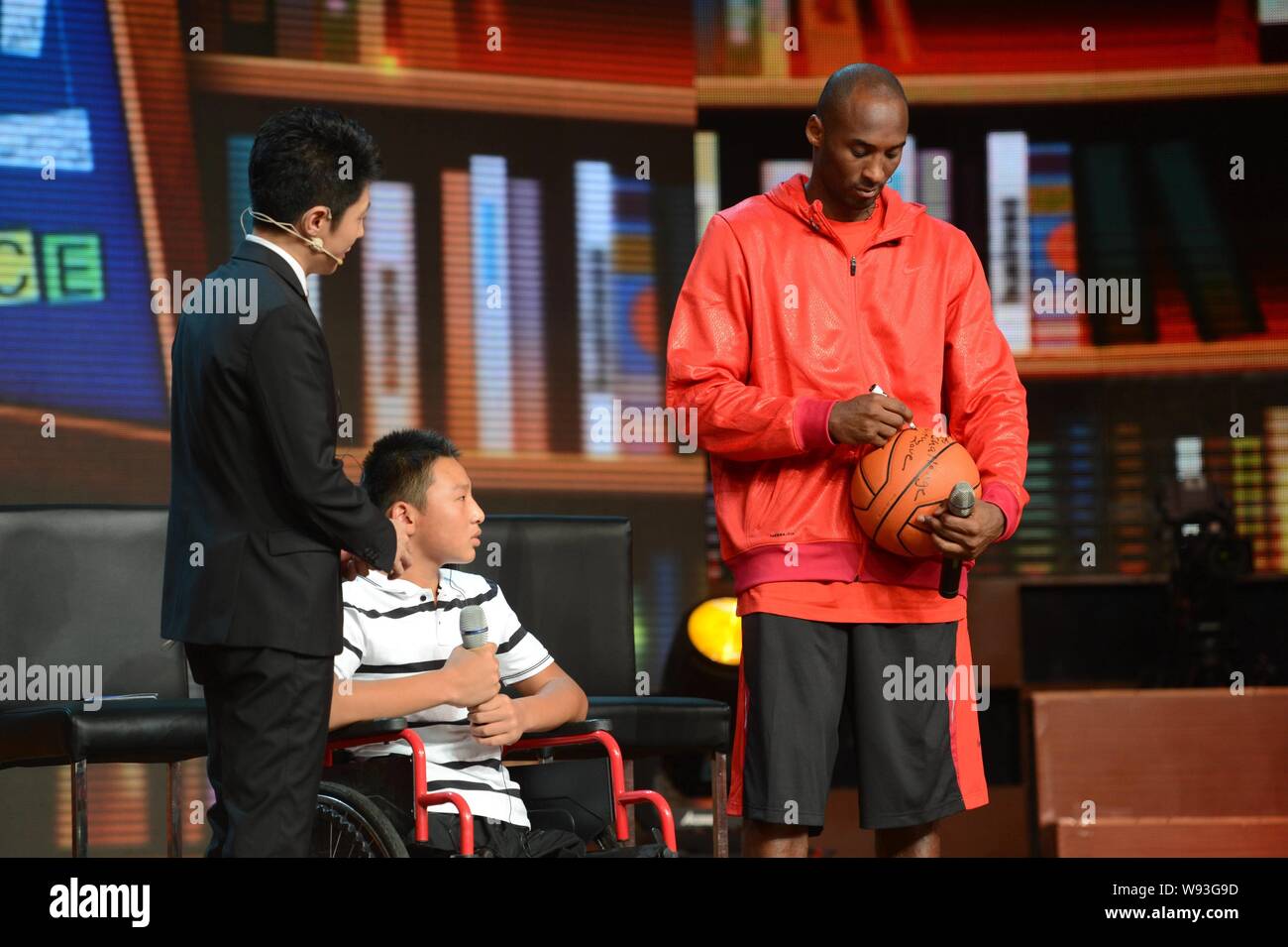 NBA star Kobe Bryant, right, autographs a basketball for a young ...