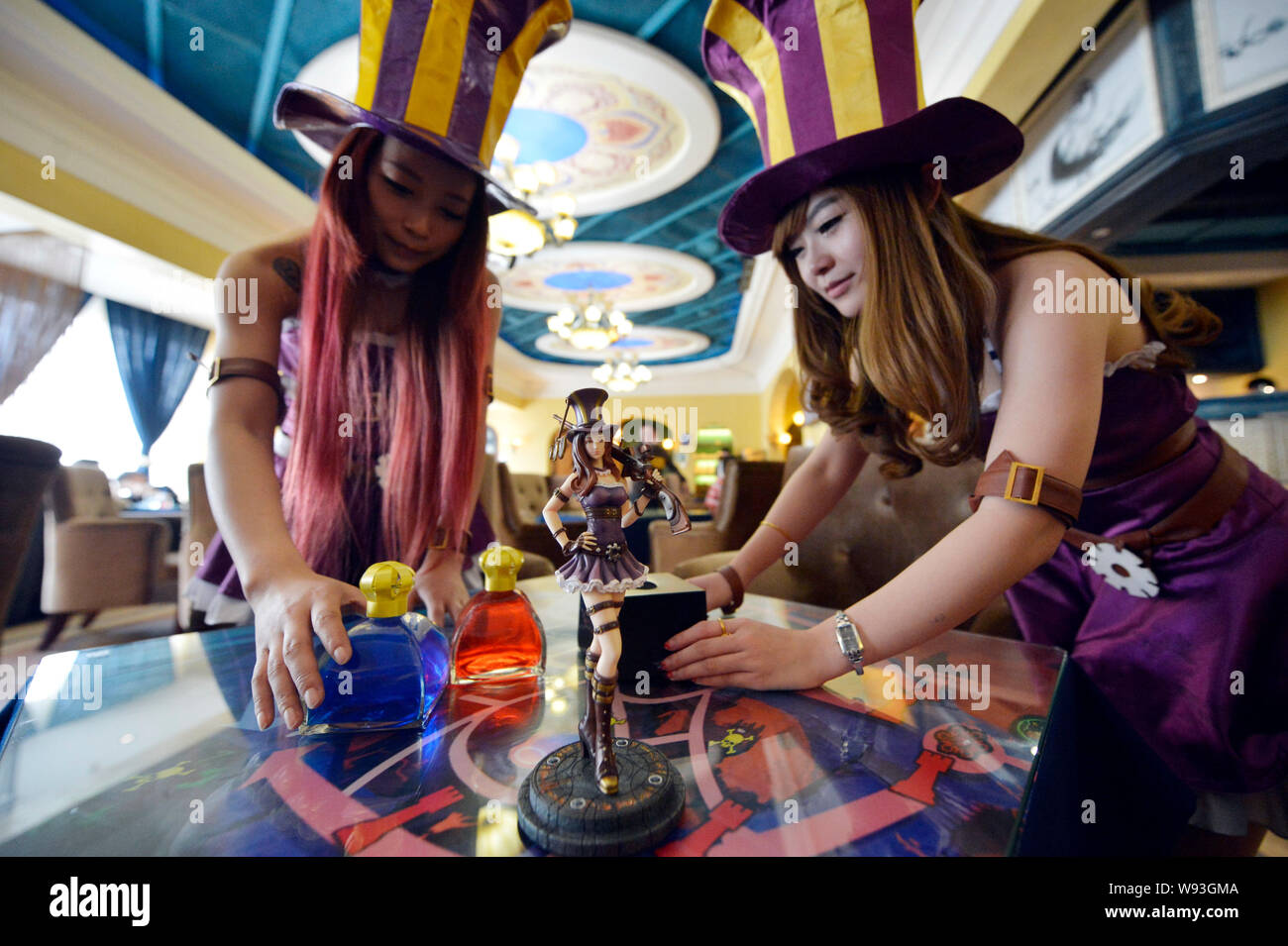 Two waitresses in costumes of game League of Legends set the table in ...