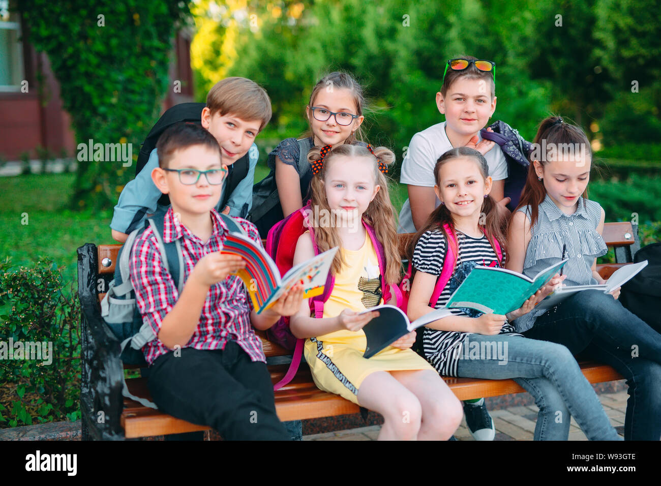 Happy Schoolmates Portrait. Schoolmates seating with books in a wooden ...