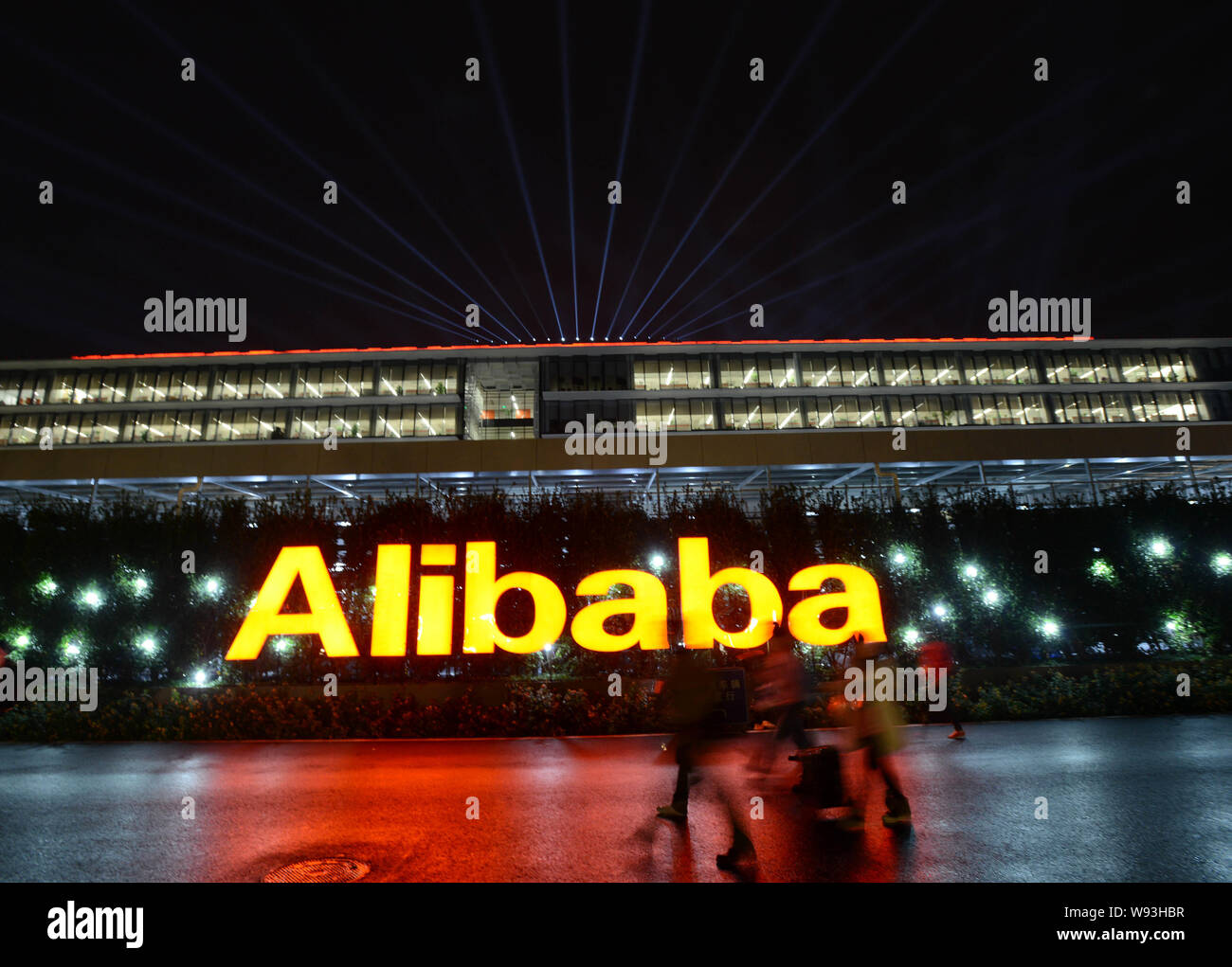 Pedestrian walk past the logo of Alibaba in front of the headquarters ...