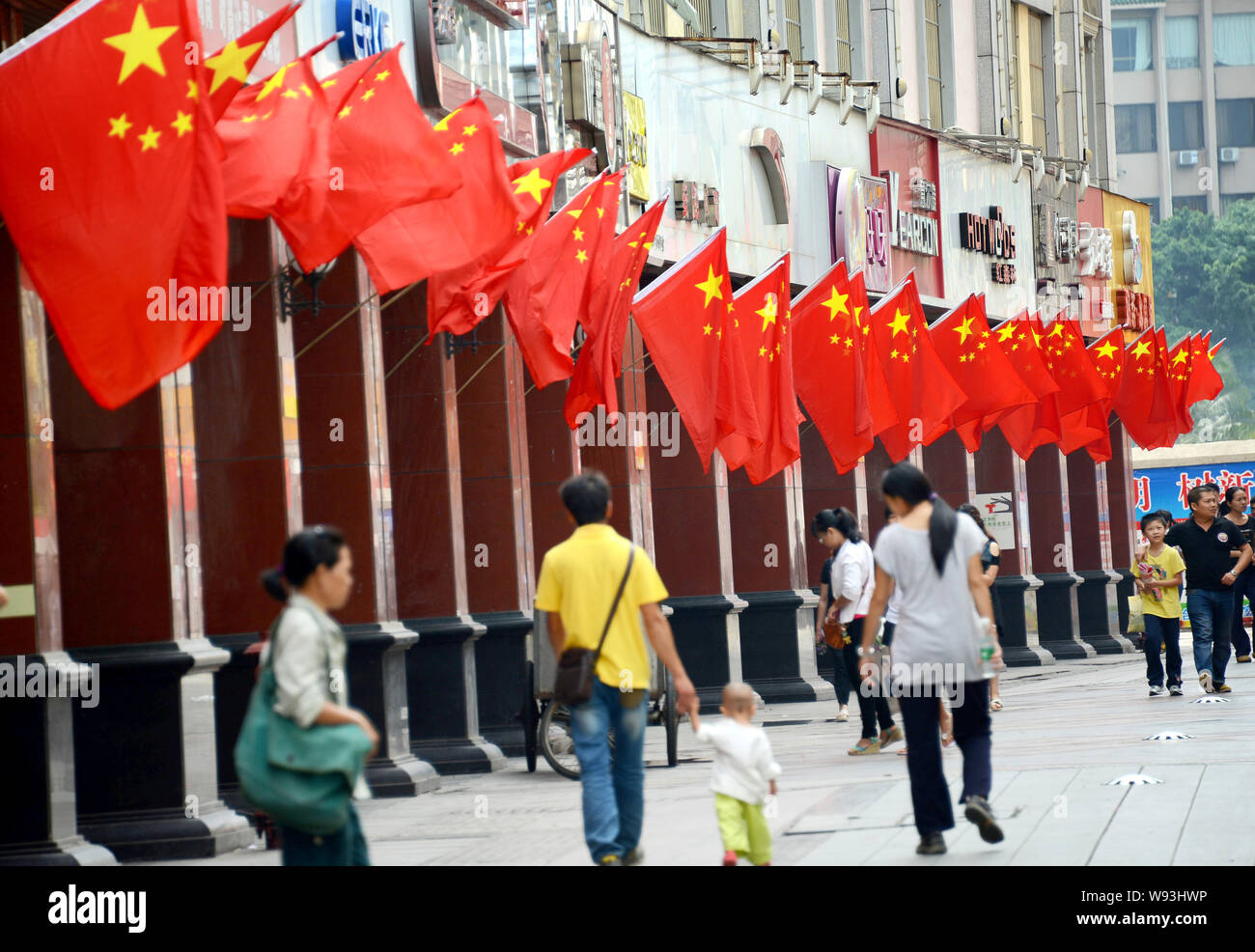 Pedestrians walk past Chinese national flags being displayed at the ...