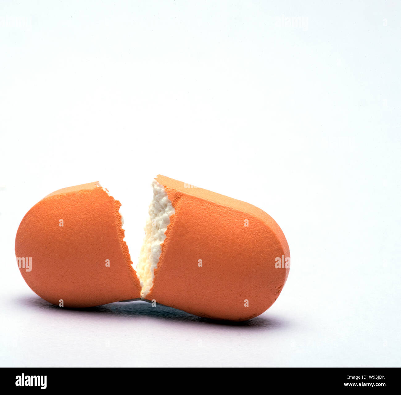 A pill capsule broken into two isolated closeup, addiction, pharmacy ...