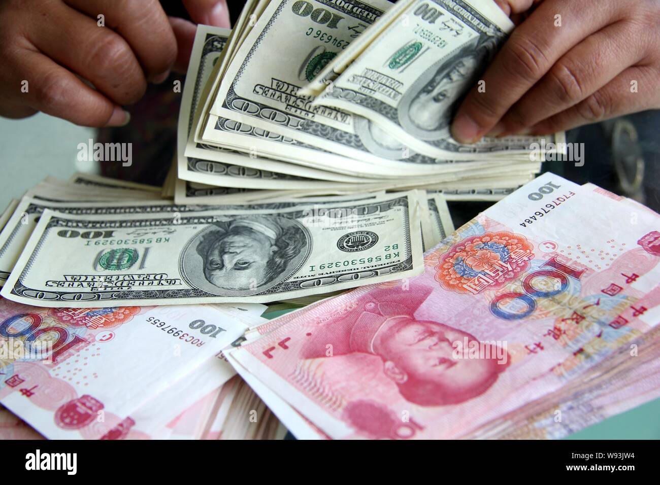 A Chinese clerk counts US dollar and RMB (renminbi) yuan banknotes at a ... A Chinese clerk counts US dollar and RMB (renminbi) yuan banknotes at a ...