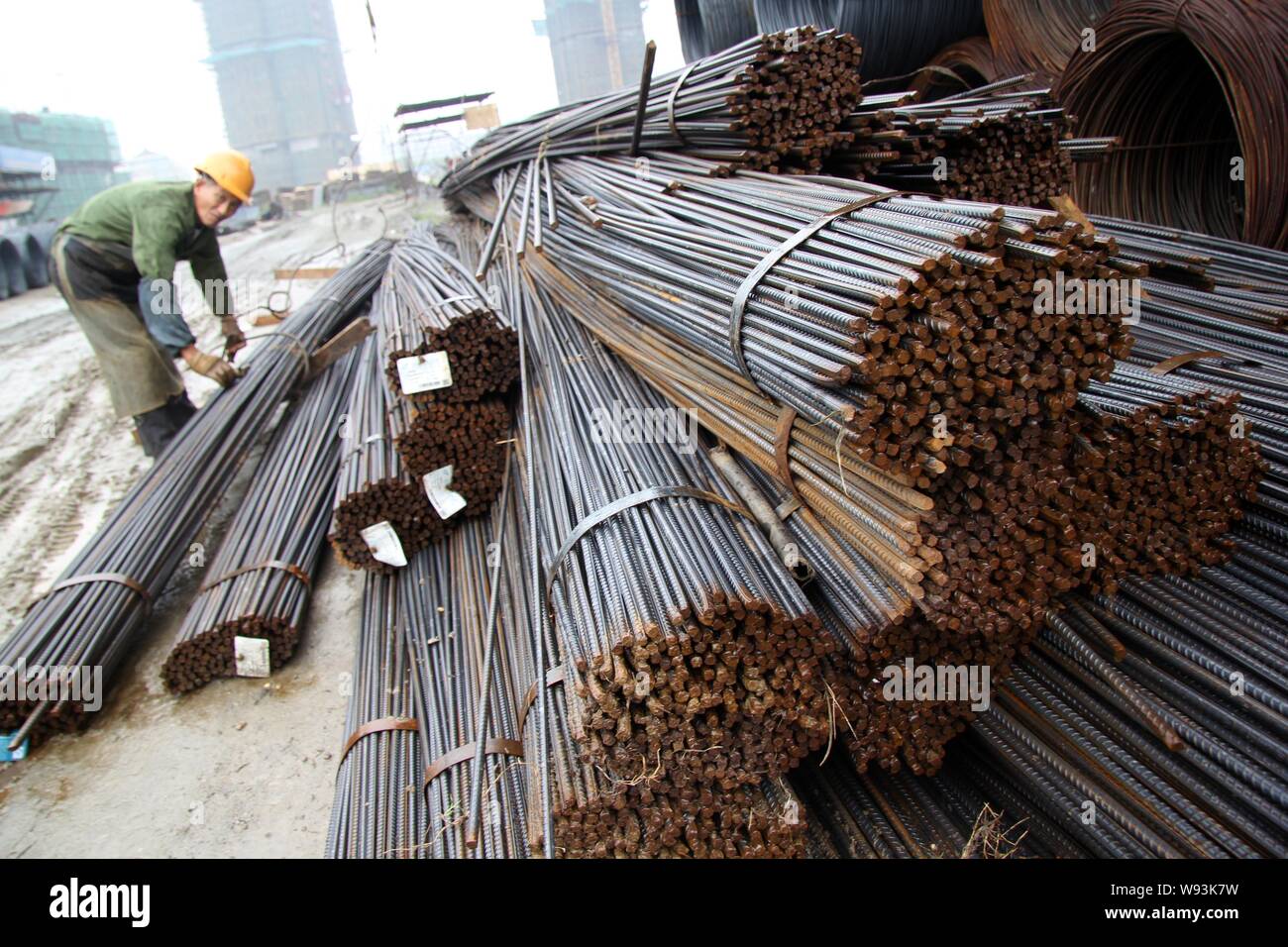 A Chinese worker fastens a cable to lift reinforcing steel rods at a ...