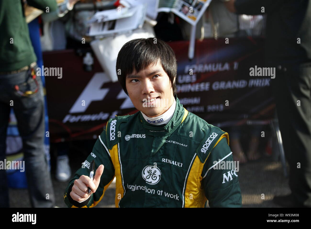 Chinese driver Ma Qinghua of Caterham gestures as he signs autographs ...