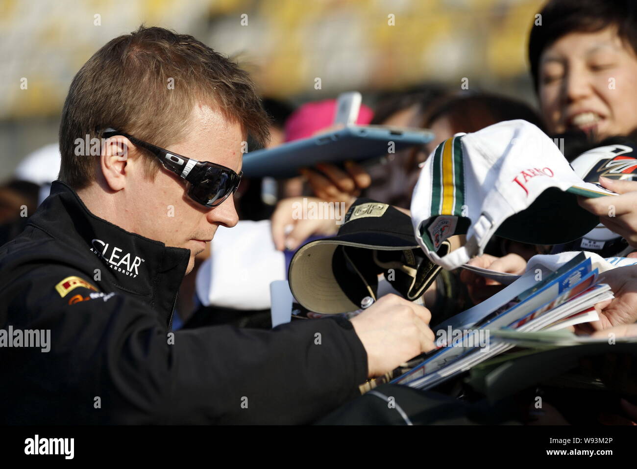 Finnish F1 driver Kimi Raikkonen of Lotus signs autographs for fans at ...