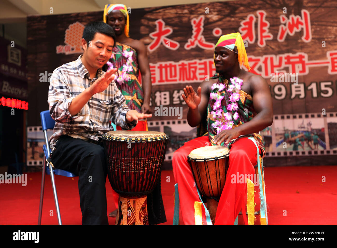 A Chinese man, left, learns to play a drum with an African drummer ...