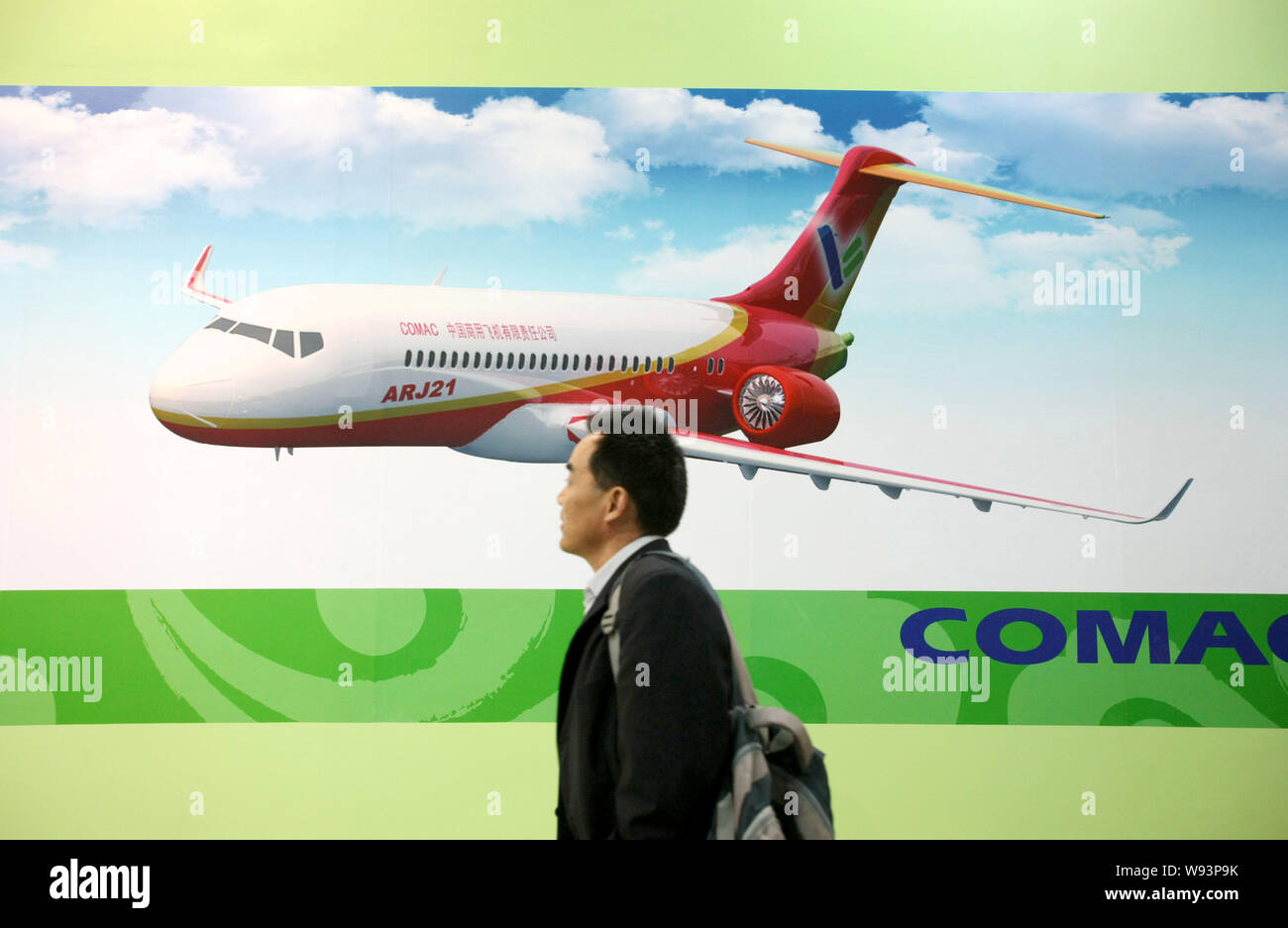 A visitor walks past an advertisement for the ARJ21 regional jet plane ...