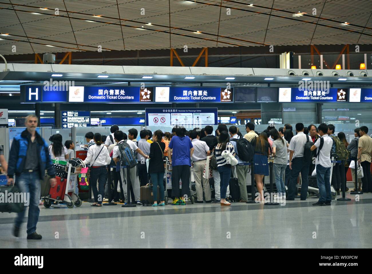 Passengers queue up to check in at check-in counters at the Beijing ...