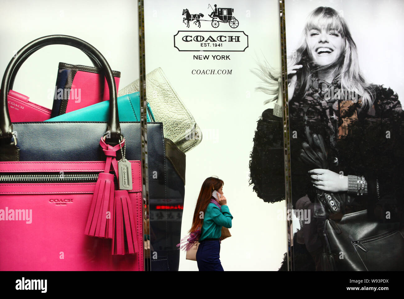 A young Chinese woman walks past a Coach store in Shanghai, China, 24 ...