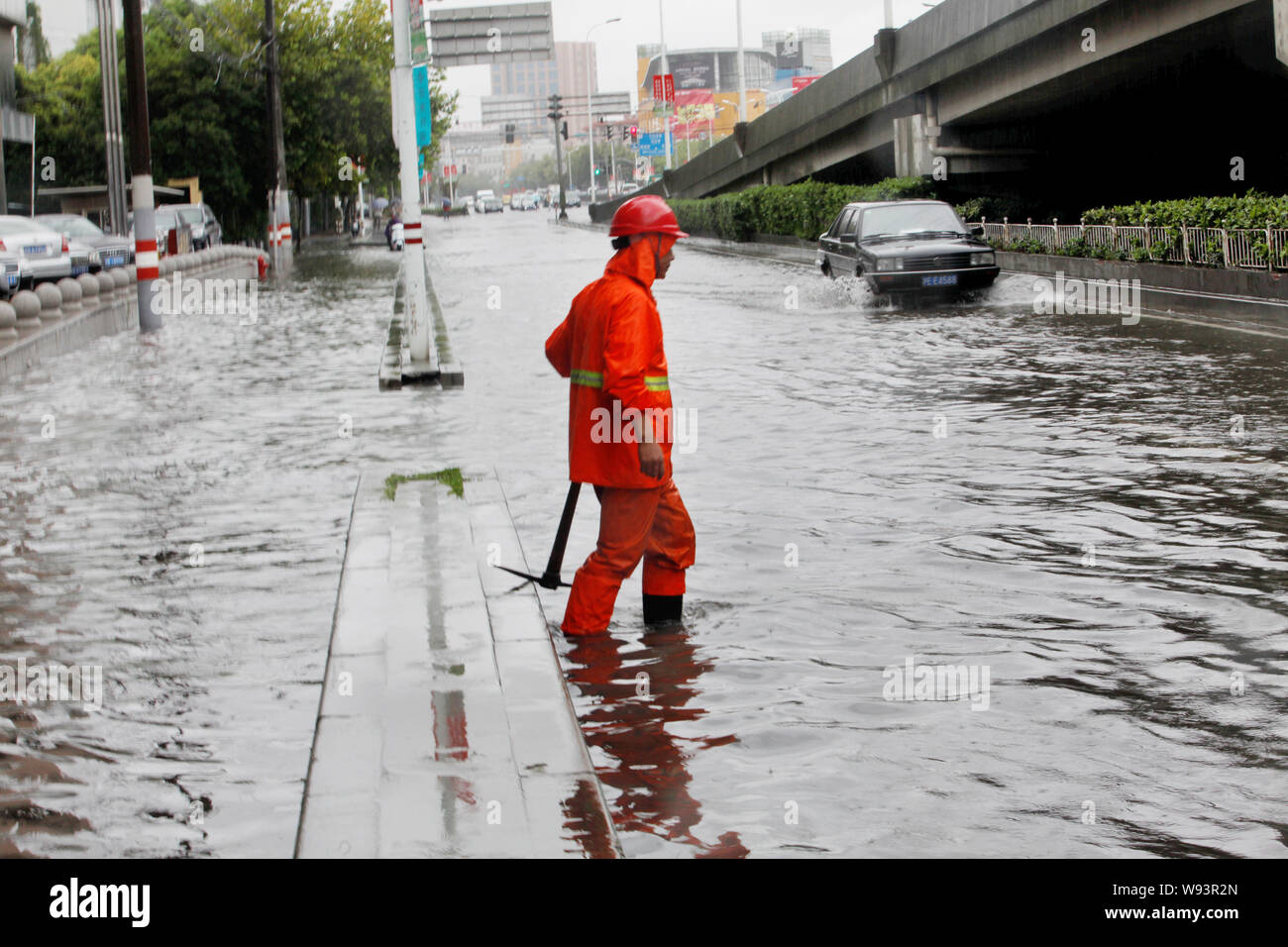 A Chinese worker walks on a flooded road in a heavy rain caused by ...