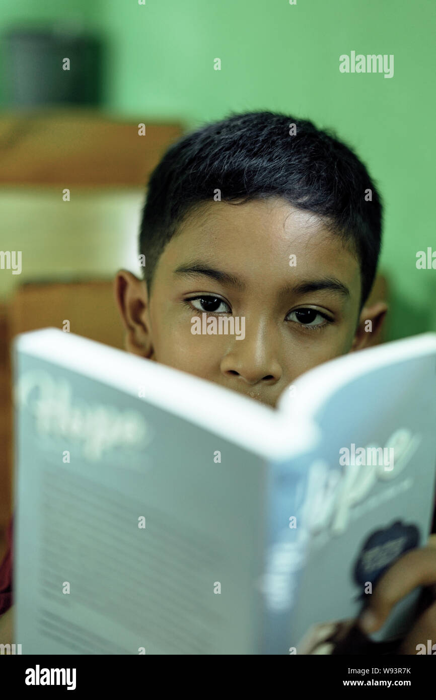 Cute little asian boy reads book in the Classroom Stock Photo - Alamy