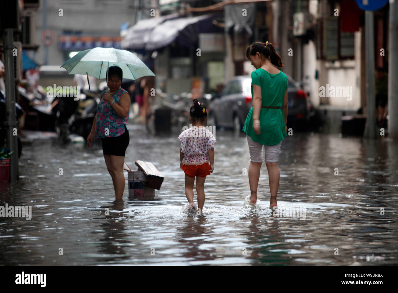 People walk on the flooded street from a heavy thunderstorm in Shanghai ...