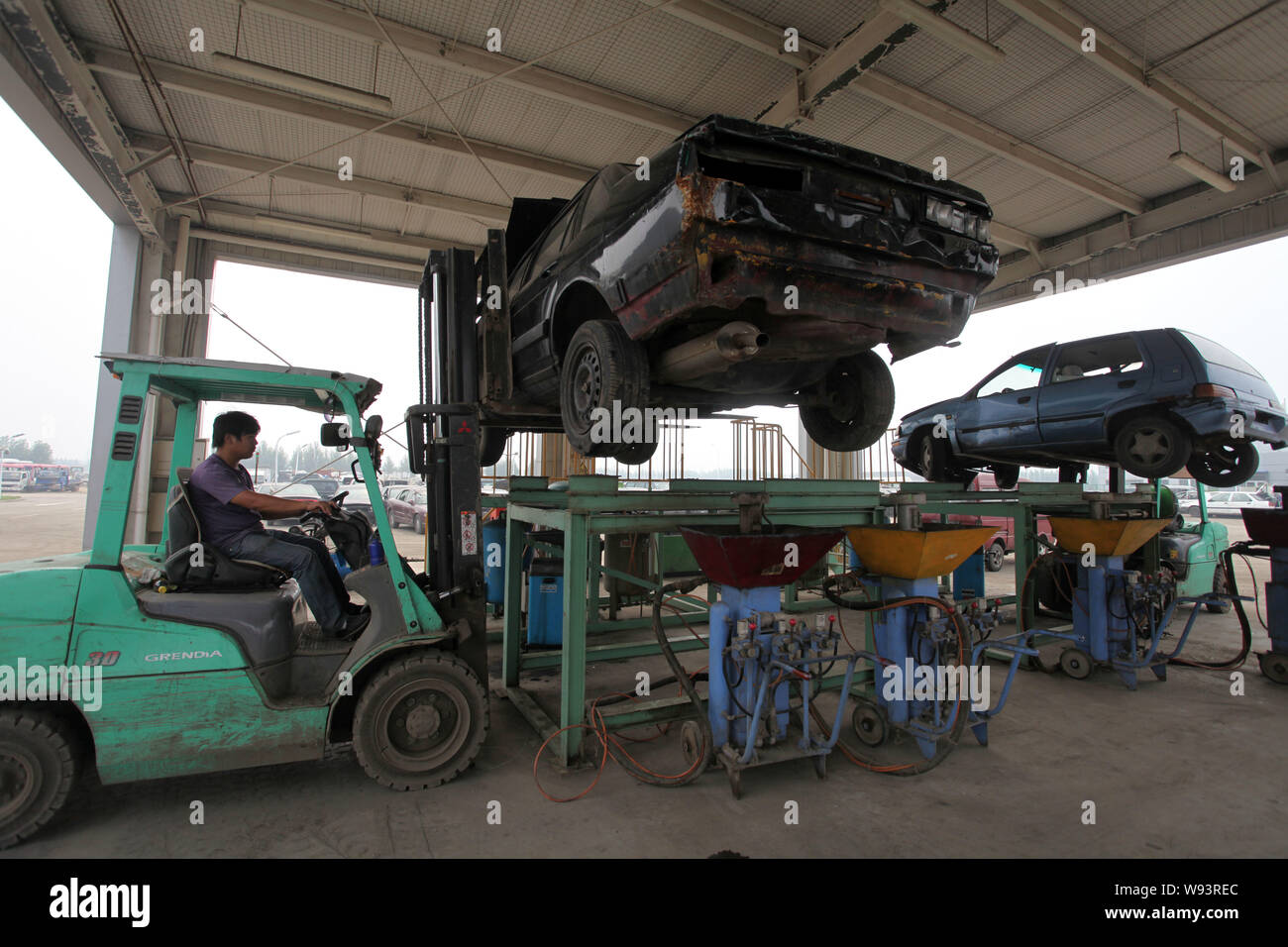 A Chinese worker drives a forklift to lift a scrap car for the release ...