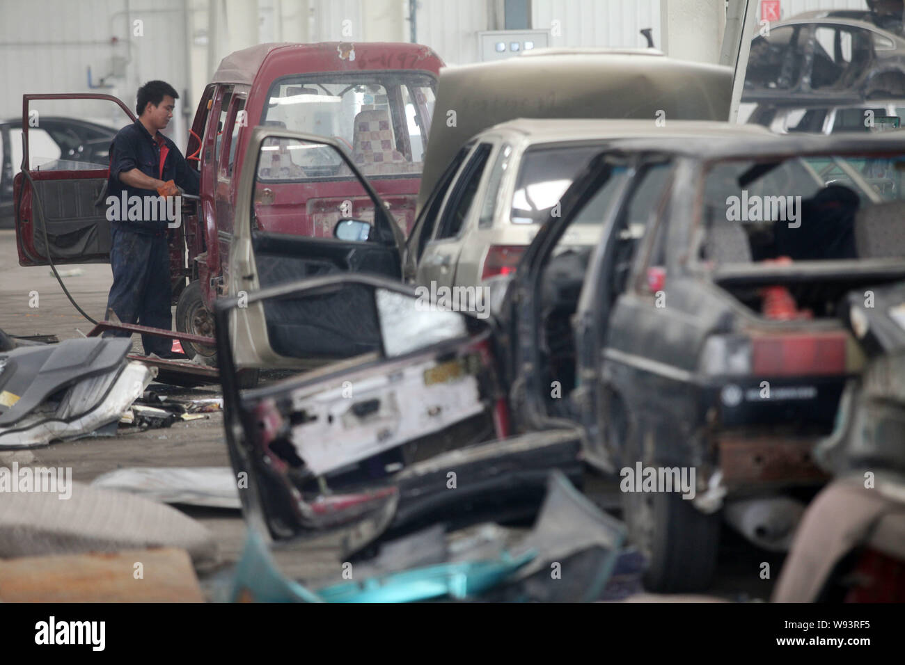 A Chinese worker disassembles a scrap car at a vehicle disassembly ...