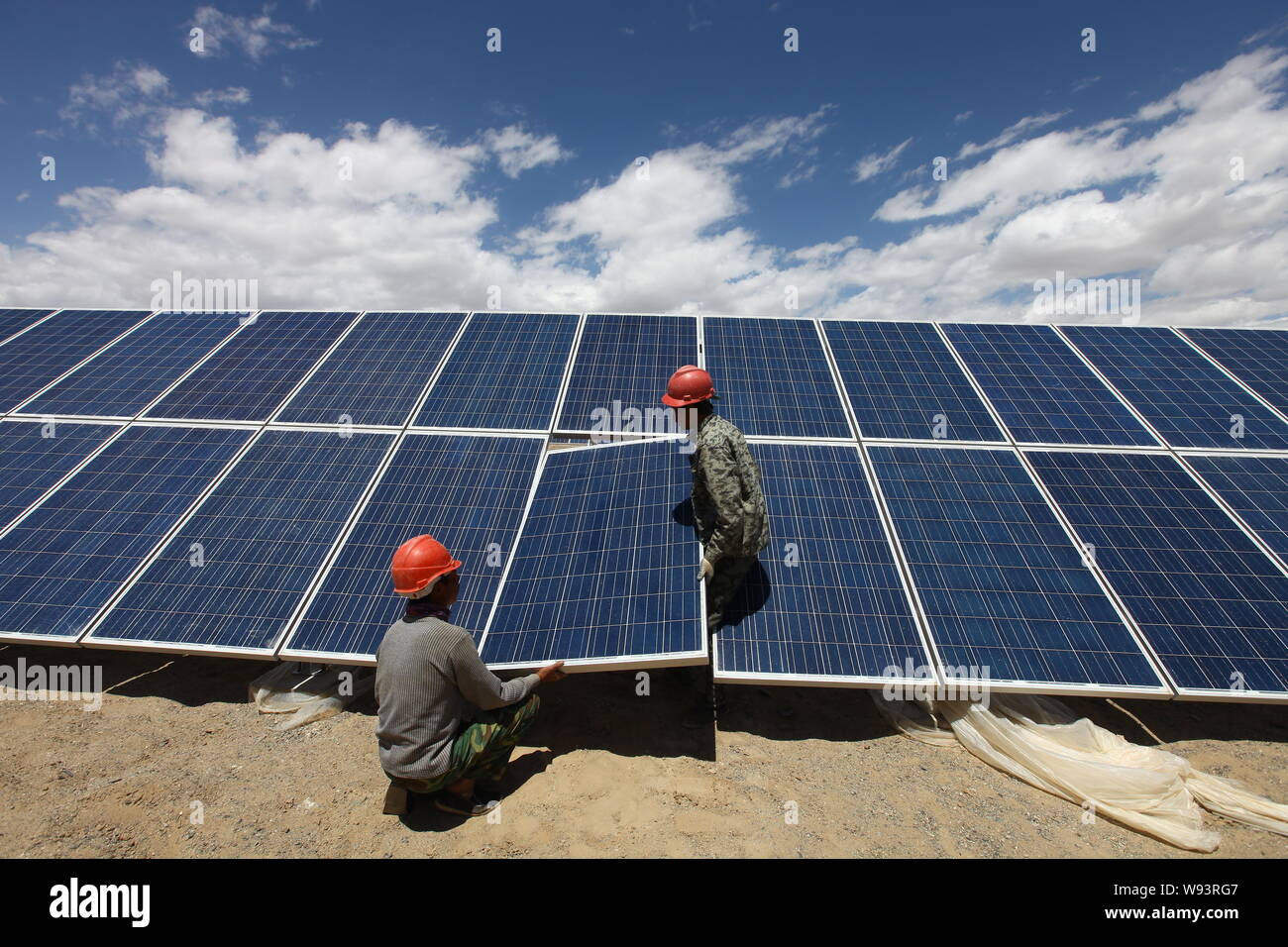 Chinese workers install a solar panel at a photovoltaic (PV) power ...